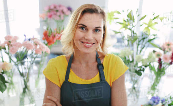 Beautiful woman florist standing in flower shop. Female florist in ...