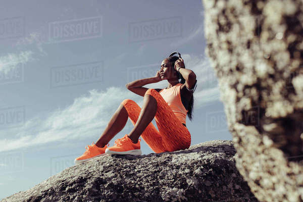 Woman relaxing and listening music on headphones after workout on the ...