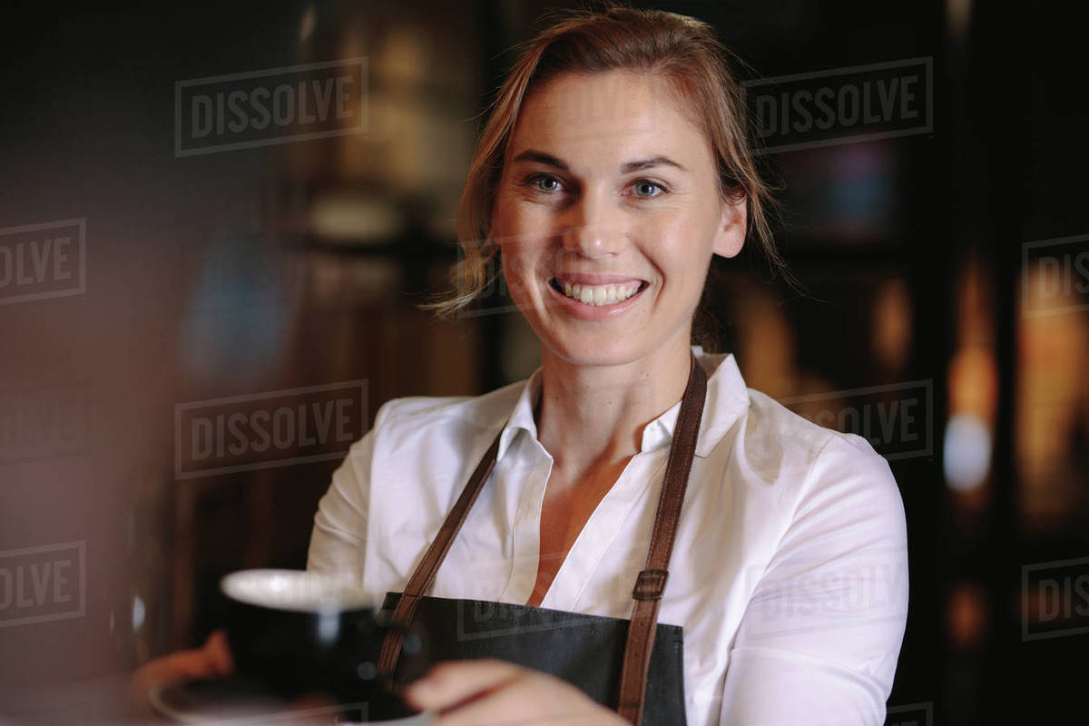 Smiling woman serving coffee inside a coffee shop. Happy coffee shop ...
