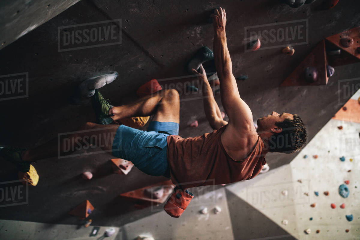 Athletic man bouldering at an indoor climbing centre. Professional ...