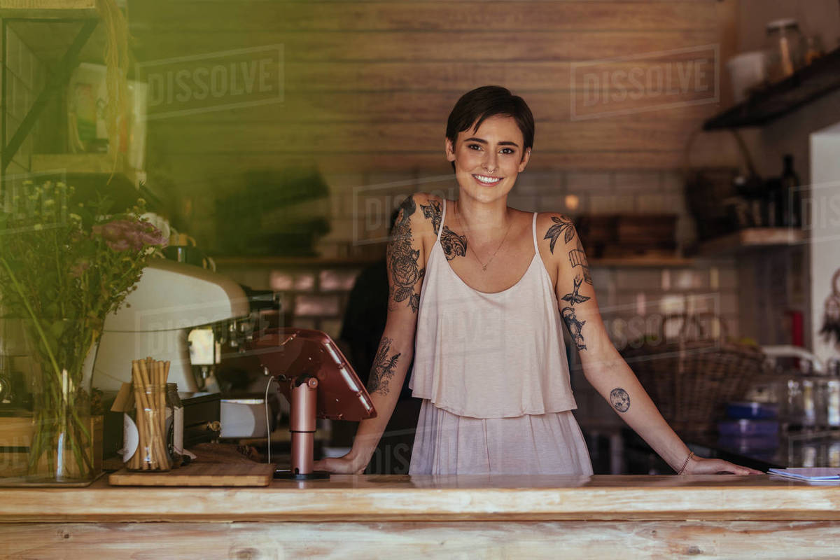 Woman standing at the counter of her cafe posing. Smiling restaurant ...