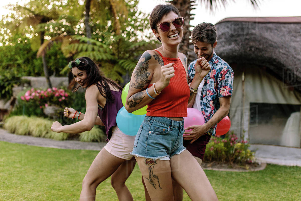Happy young woman enjoying at a party with friends playing balloon ...