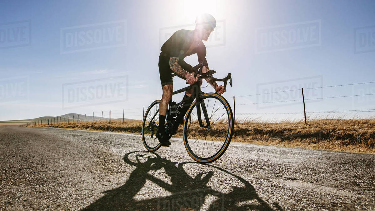 Low angle shot of male athlete cycling on country road. Professional ...