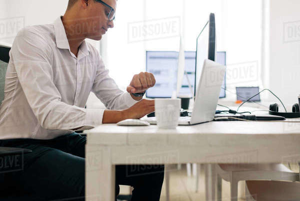 Software developer sitting at his office desk working on laptop and ...