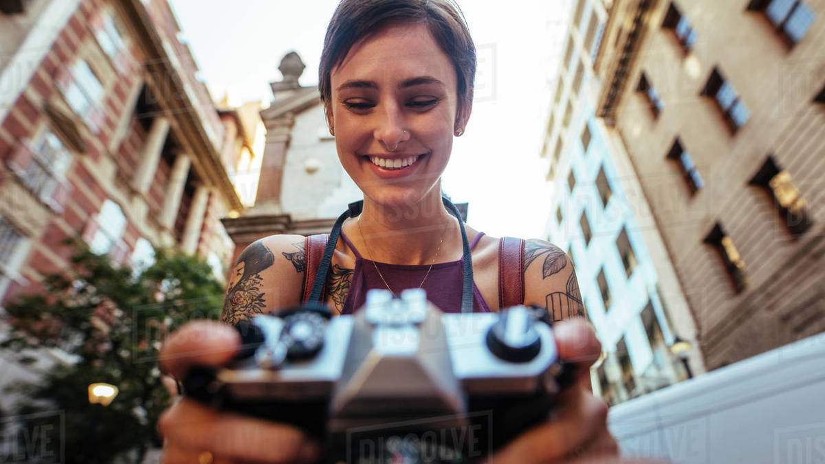 Close up of a smiling woman tourist taking photograph using a camera ...