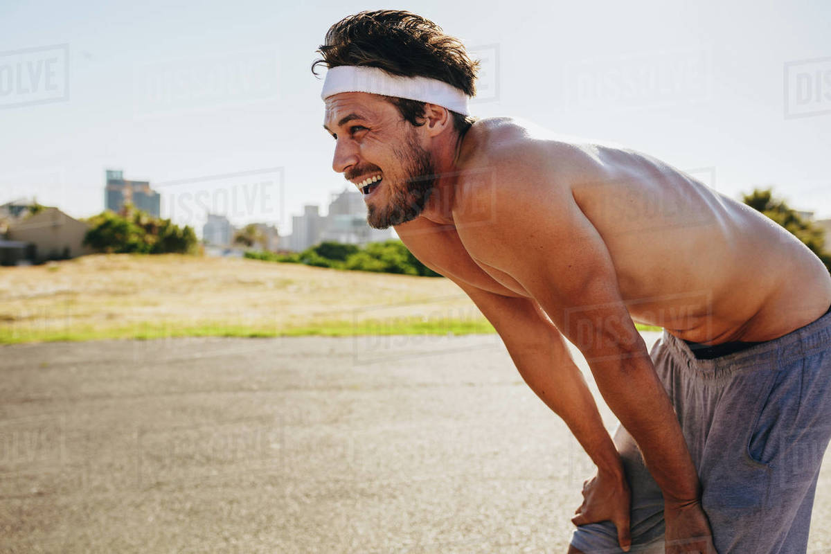 Athlete relaxing with hands resting on knees. Tired basketball player ...