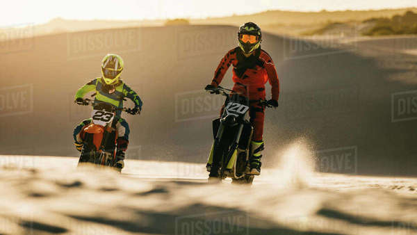 Two motocross riders racing bikes in desert. Professional dirt bikers ...