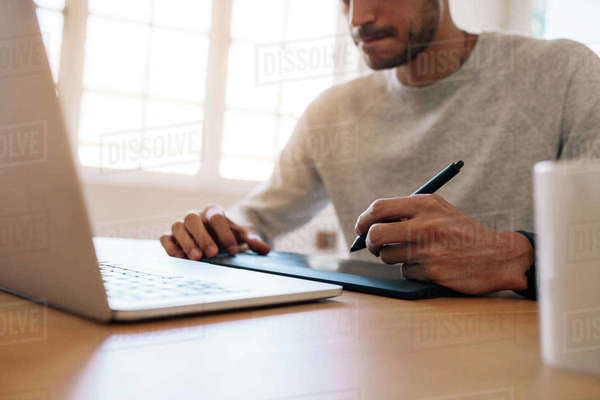 Man writing on a digital writing pad connected to a laptop sitting on a ...