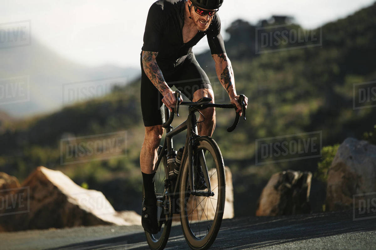 Professional male cyclist riding his bike on a mountain road. Sportsman ...
