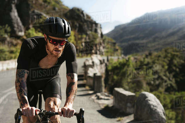 Strong cyclist training on curvy mountain roads. Sportsman cycling road ...