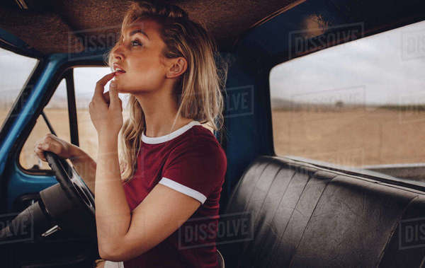 Woman looking into rear view mirror while driving a car. Beautiful ...