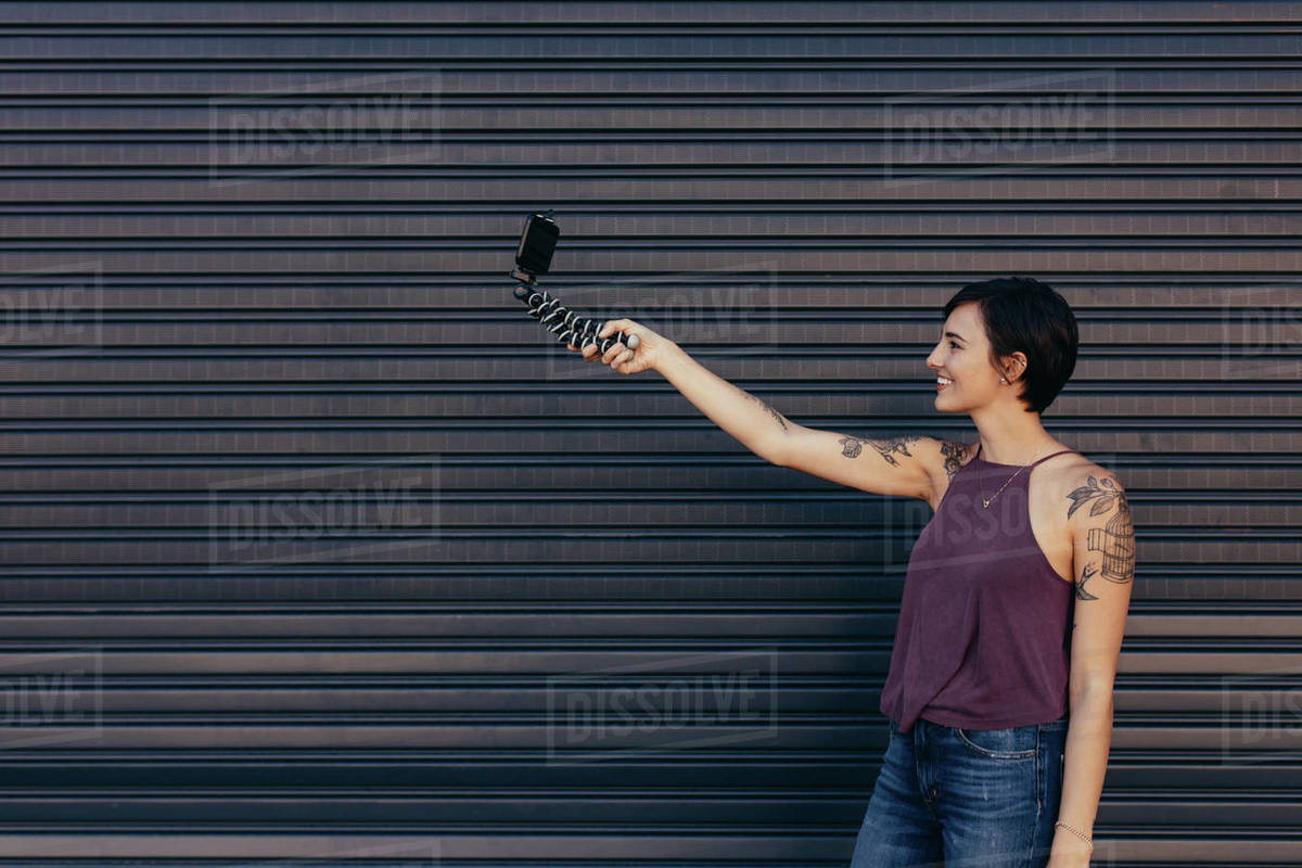 Female blogger making a video using her smart phone mounted on flexible ...