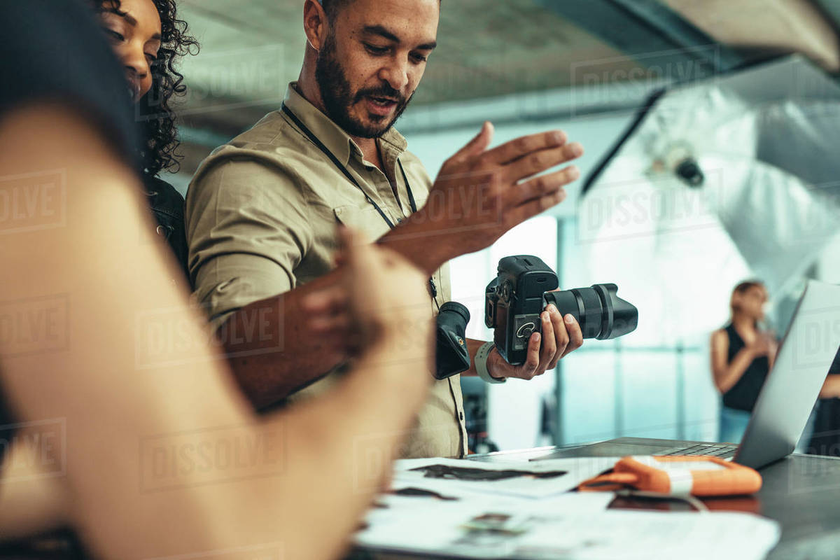 Photographer holding a digital camera doing a review of the photo shoot ...