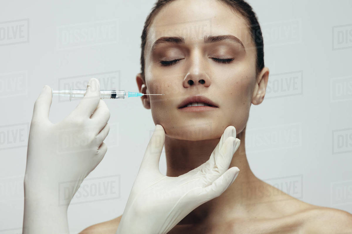 Close up of female face getting injected by syringe. Beautiful woman ...