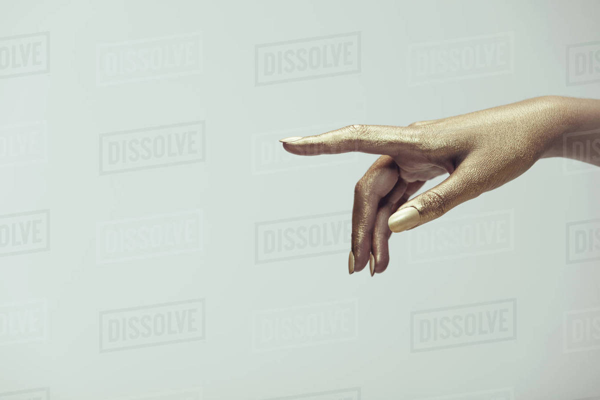 Golden painted hand pointing over grey background. Female hand in ...