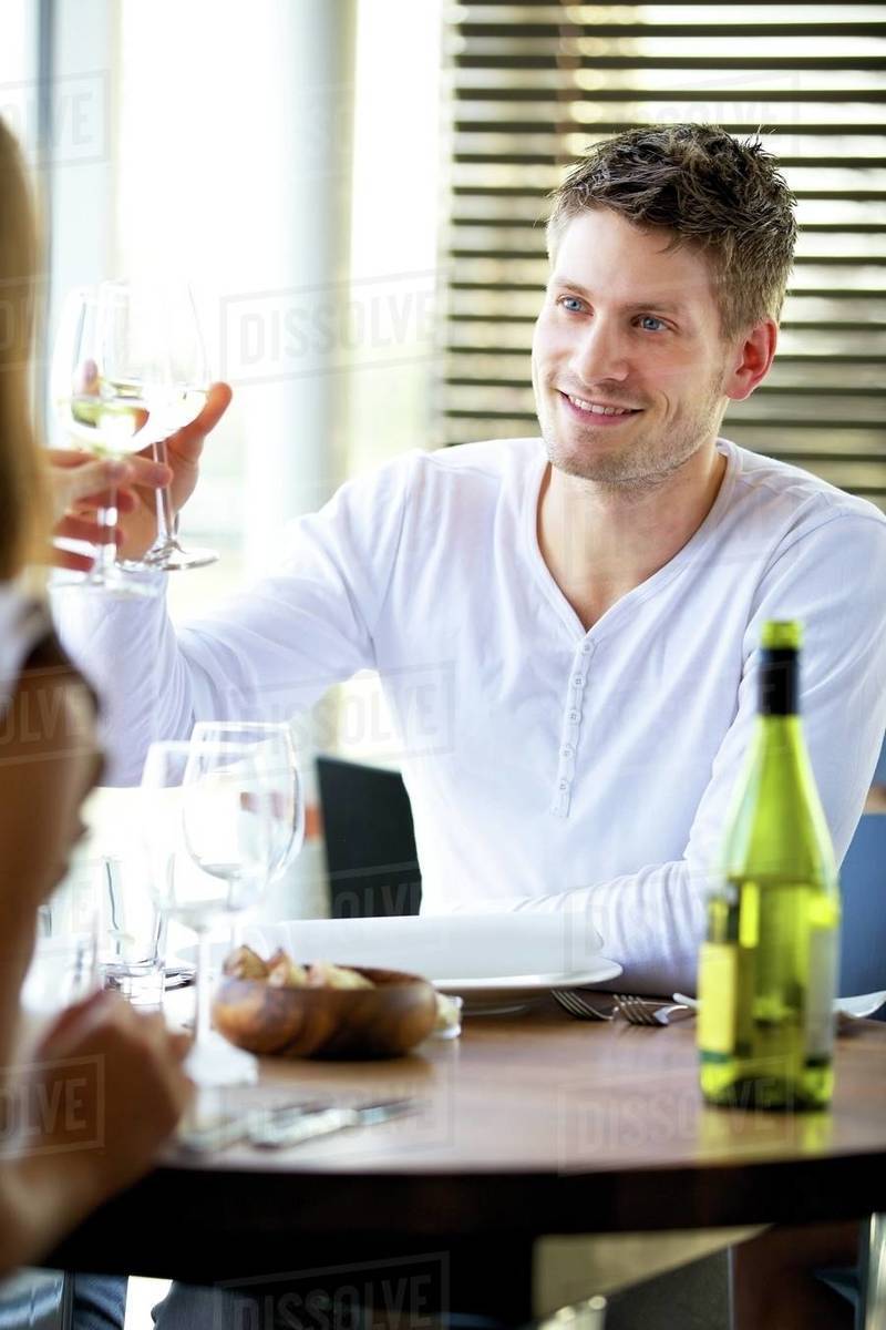 Portait of a man toasting with a glass of wine at a restaurant ...