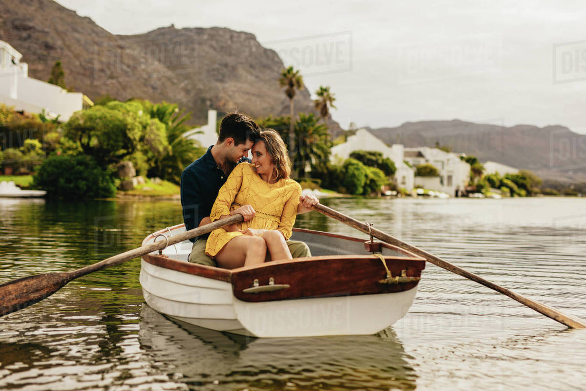 Young couple enjoying their boat date in a lake. Couple in love sitting ...