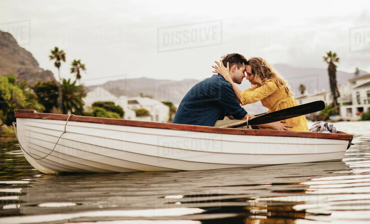 Young couple sitting together in a boat touching their heads. Couple in ...