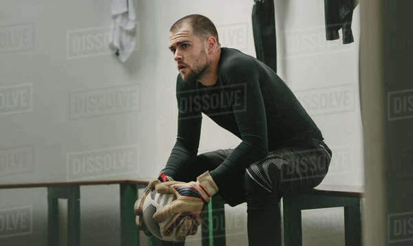 Goalkeeper sitting in a room holding a football and thinking. Soccer ...