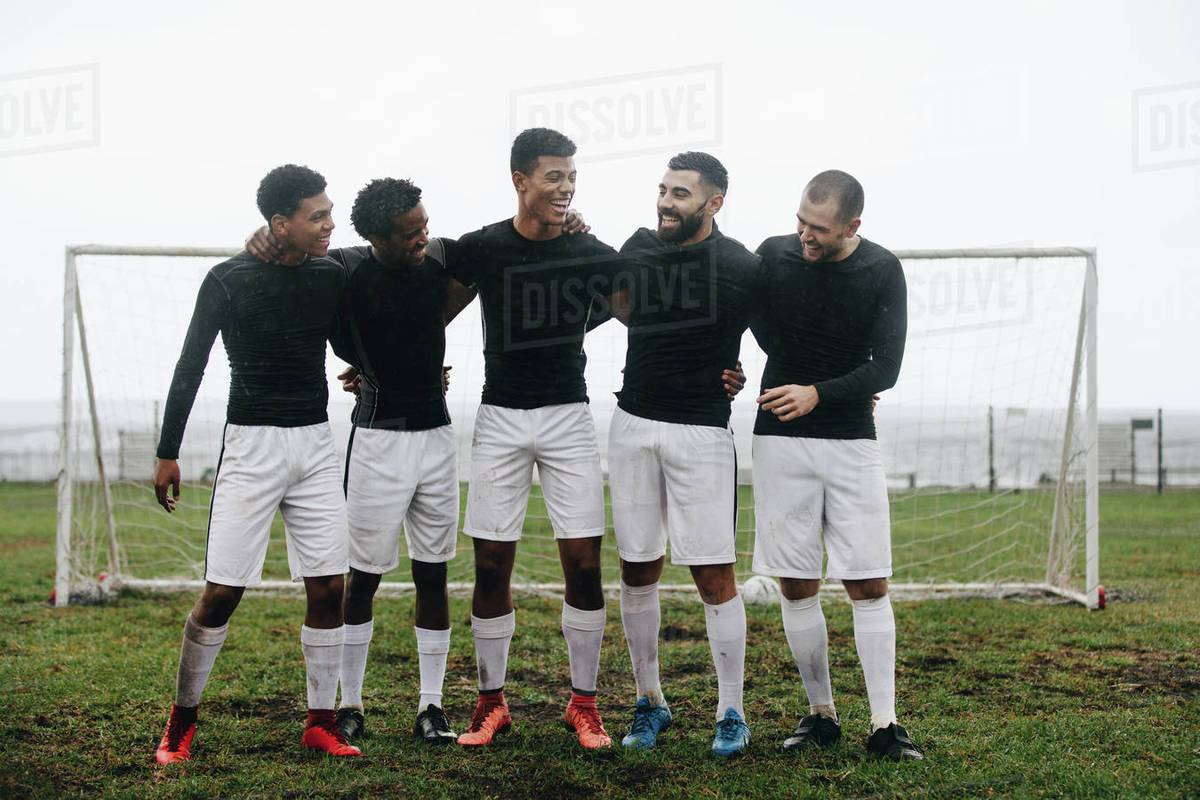 Soccer players standing together side by side near the goalpost and ...