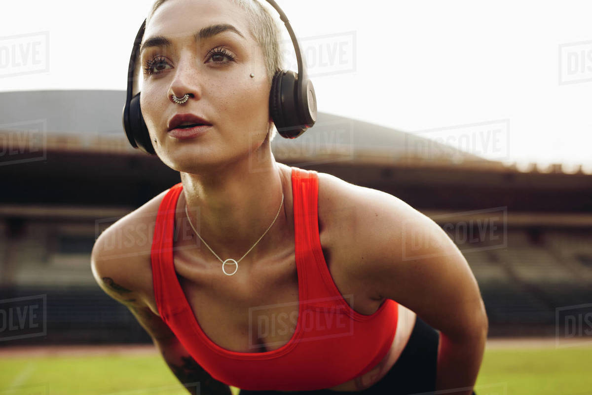Fitness woman training in a stadium bending forward with hands on knees ...