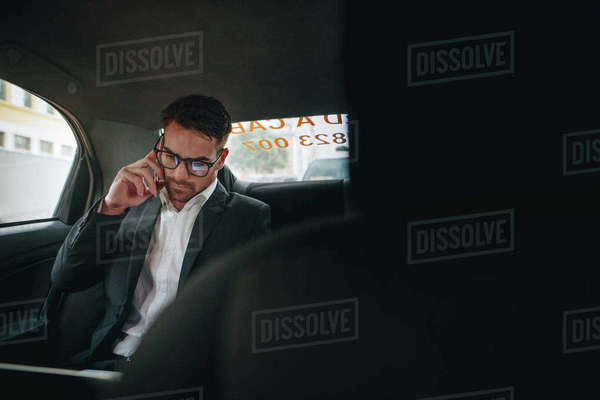 Businessman managing office work on the move sitting in a cab ...