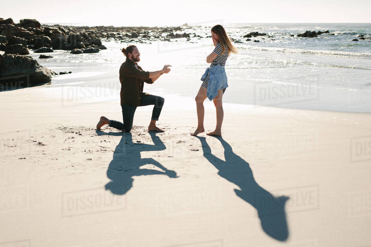 Man kneeling and proposing to woman by the sea. Man making marriage ...