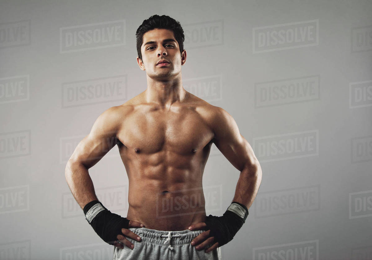 Portrait of muscular man standing with his hands on hips looking at ...