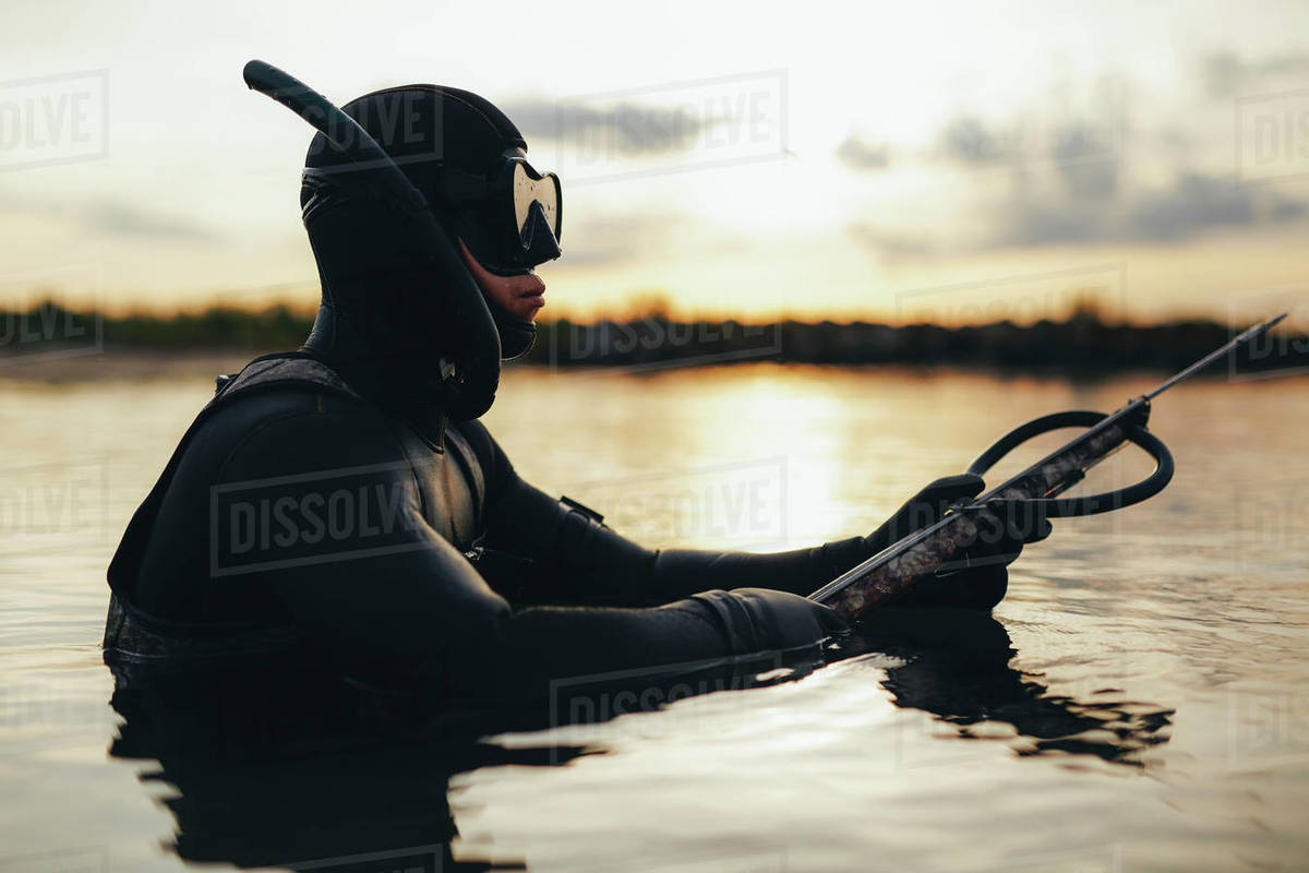 Underwater fisherman in sea. Diver wearing scuba gear holding speargun ...