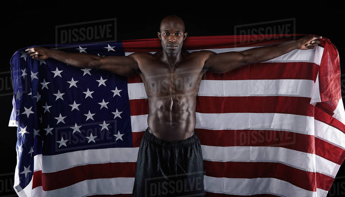 Portrait of african muscular male holding American Flag against black ...