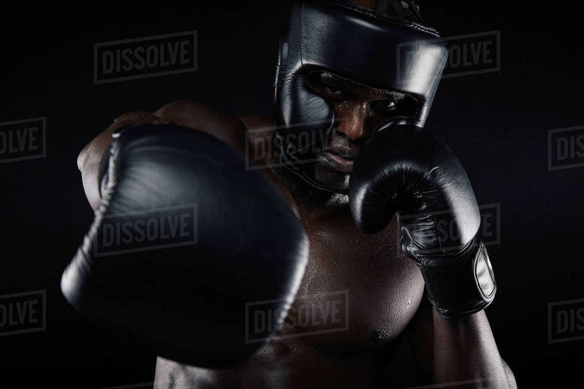 Portrait of african male practicing boxing looking at camera against ...