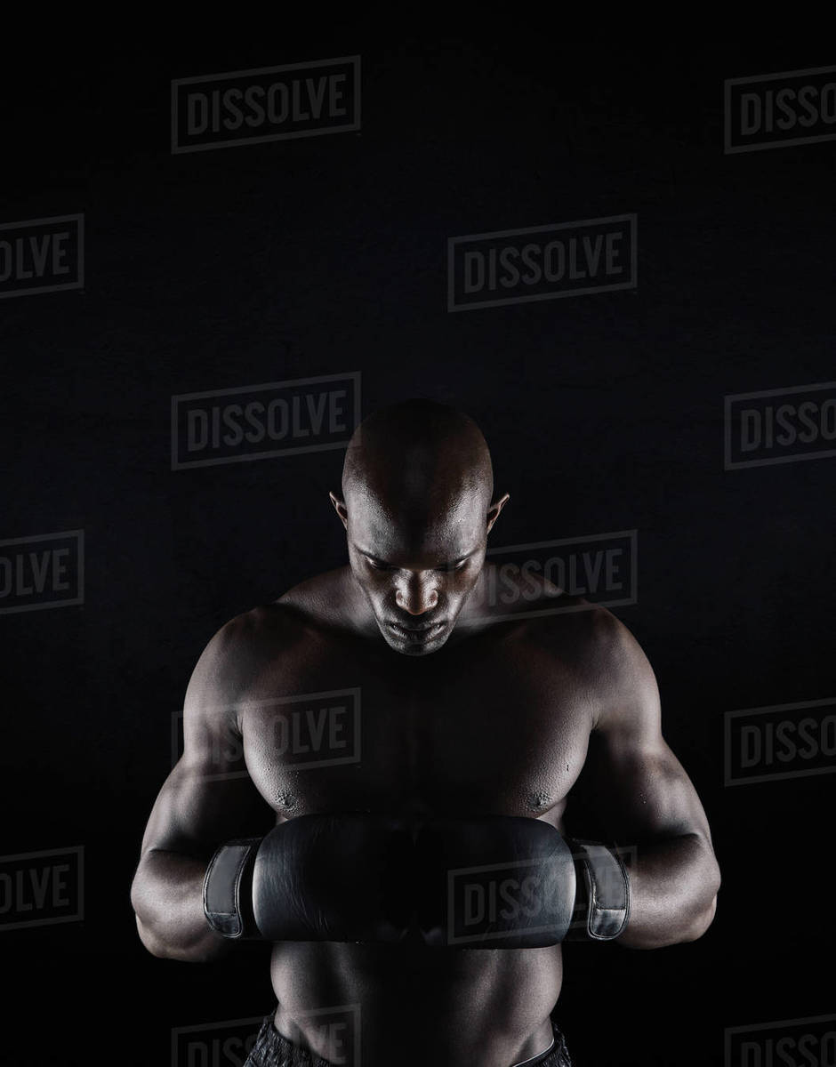 Portrait of professional young male boxer looking down on black ...