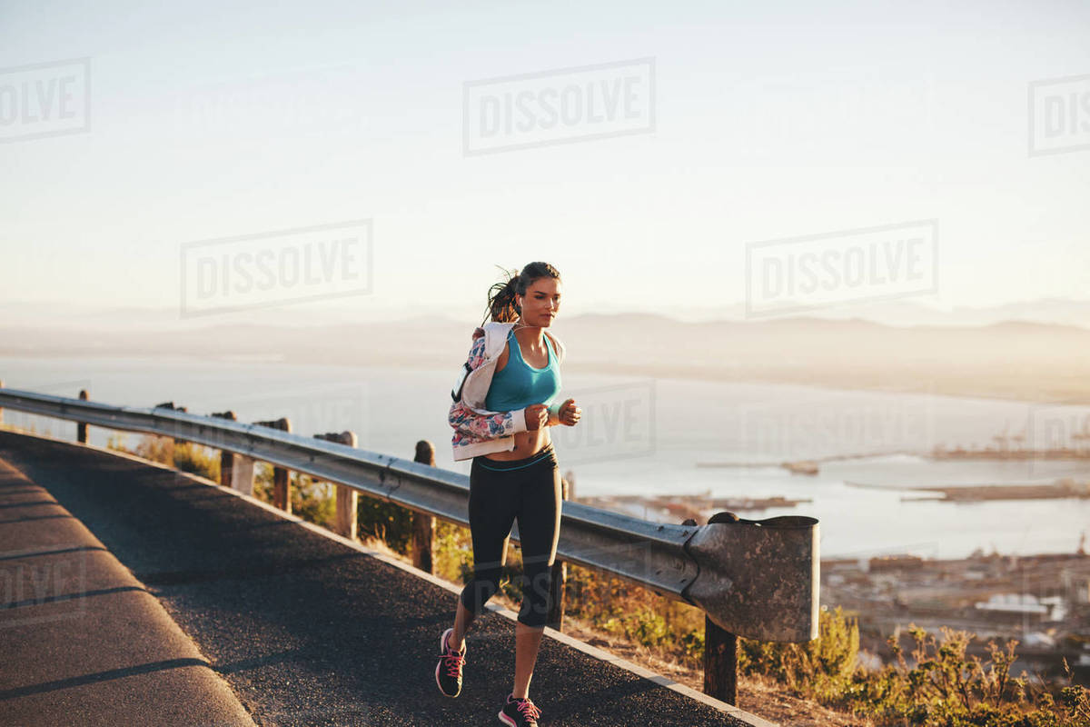 Shot of fitness woman running outdoors. Caucasian female jogging in ...