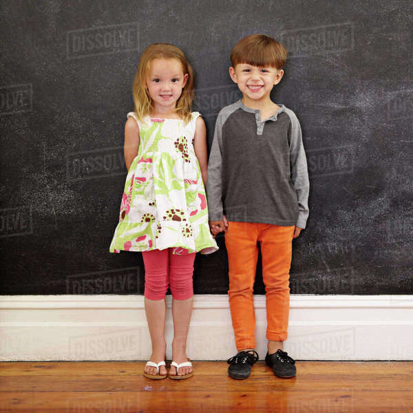 Full length shot of two little kids standing together against a ...