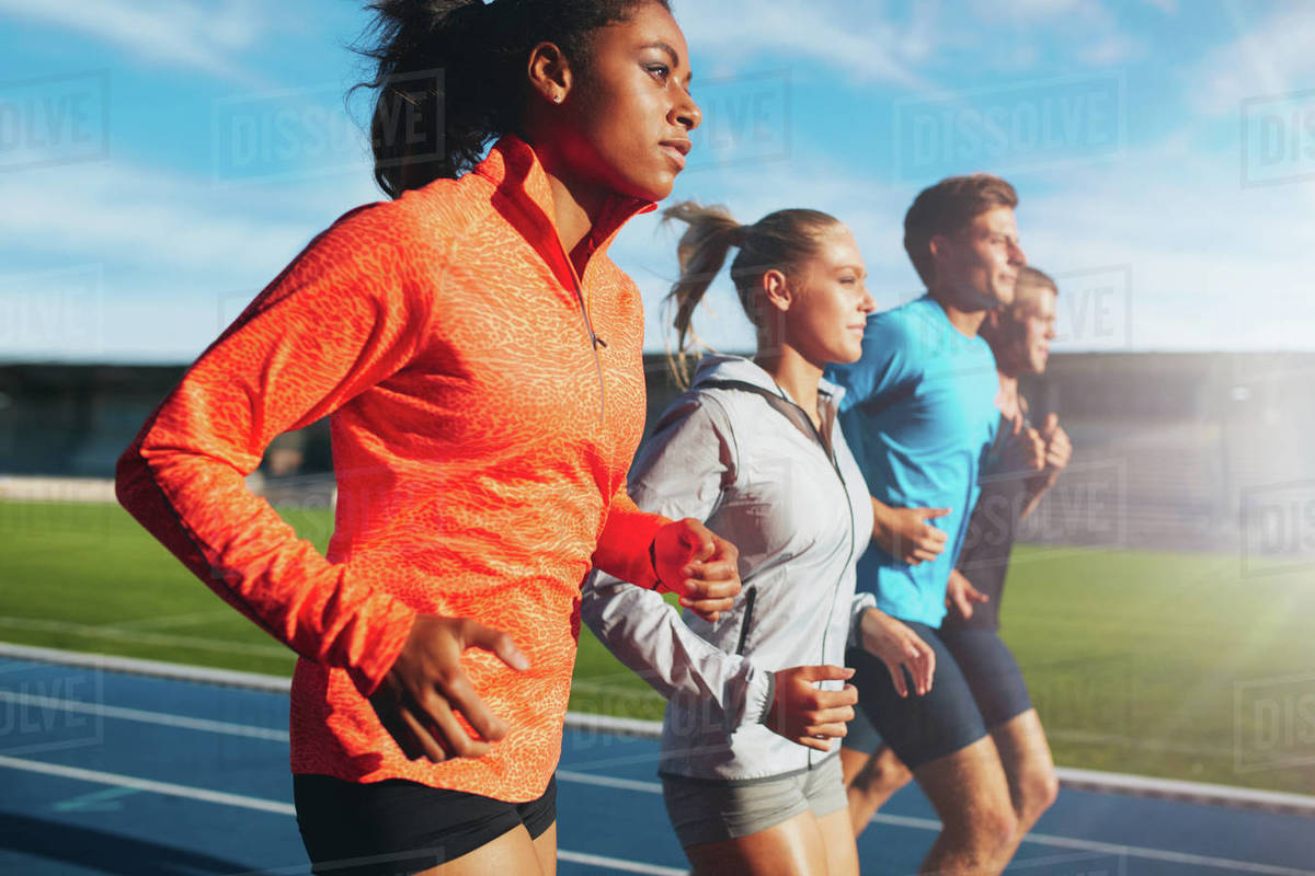 Young african woman running with her team on running track in stadium ...