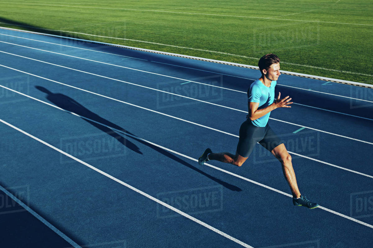 Shot of a young male athlete training on a race track. Sprinter running ...