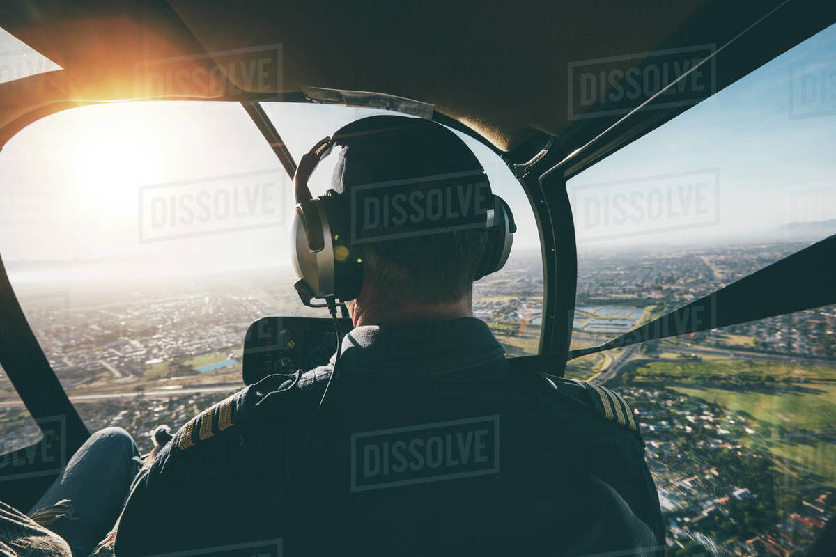 Rear view of a male pilot flying a helicopter on sunny day. - Stock ...