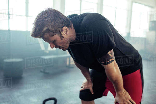 Portrait of a young fitness man exhausted after intense workout at ...