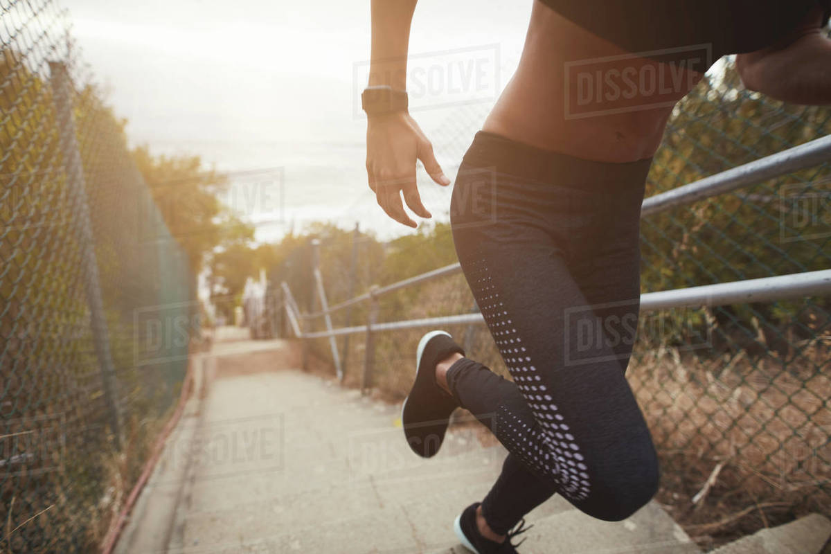 Cropped shot of female runner running up steps for exercise. Woman ...