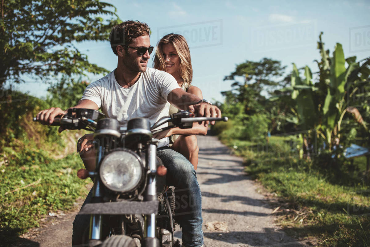 Shot of young couple on motorcycle. Man riding on a motorbike with ...
