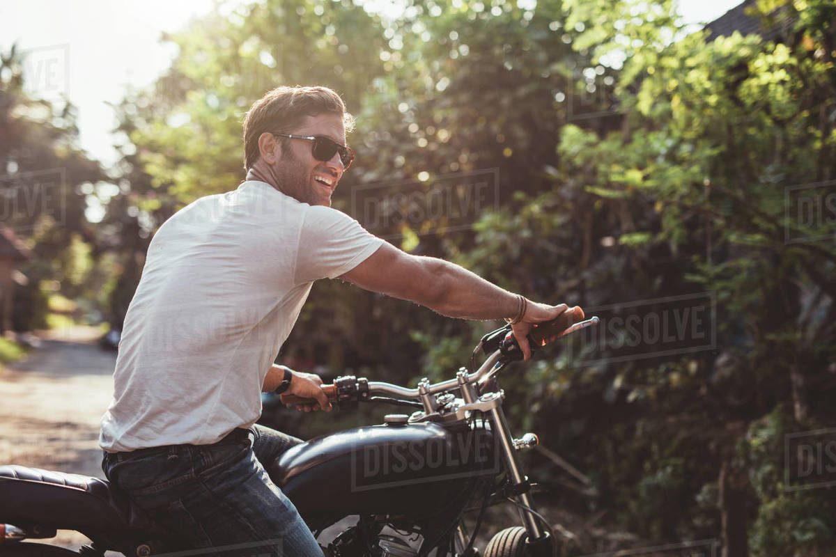Portrait of handsome young man on motorcycle. Happy caucasian male on ...
