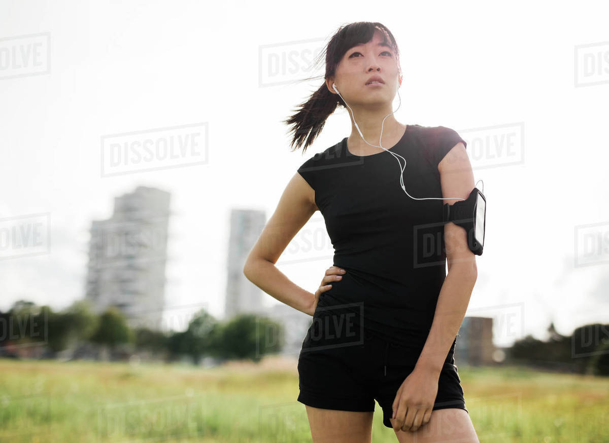 Outdoor shot of female runner standing in urban park. Chinese woman in ...