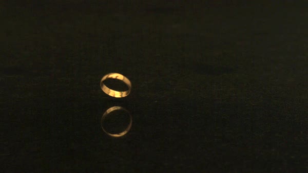 A gold ring falling through the air, bouncing and spinning on granite ...