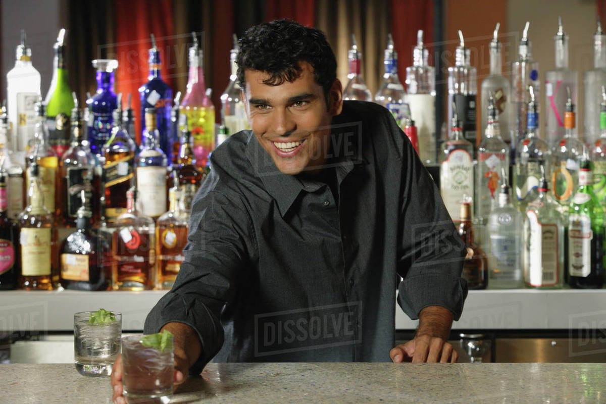 Hispanic male bartender serving drink - Stock Photo - Dissolve