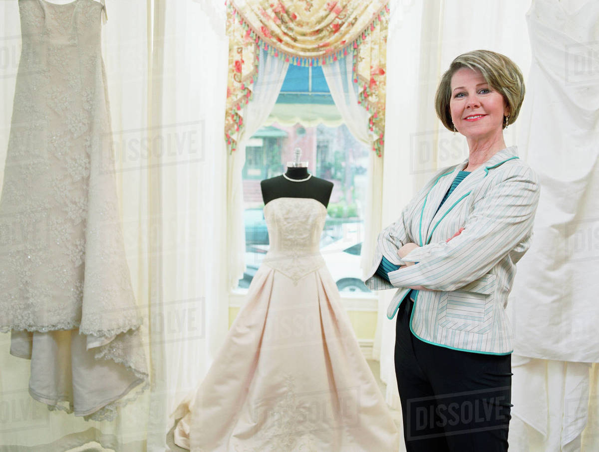 Employee smiling for the camera in bridal boutique - Stock Photo - Dissolve