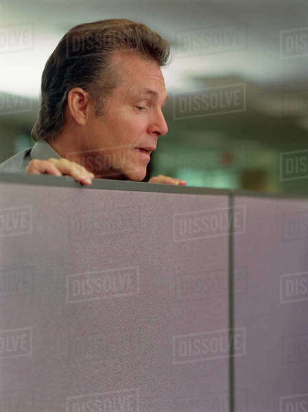 Businessman looking over cubicle wall - Stock Photo - Dissolve