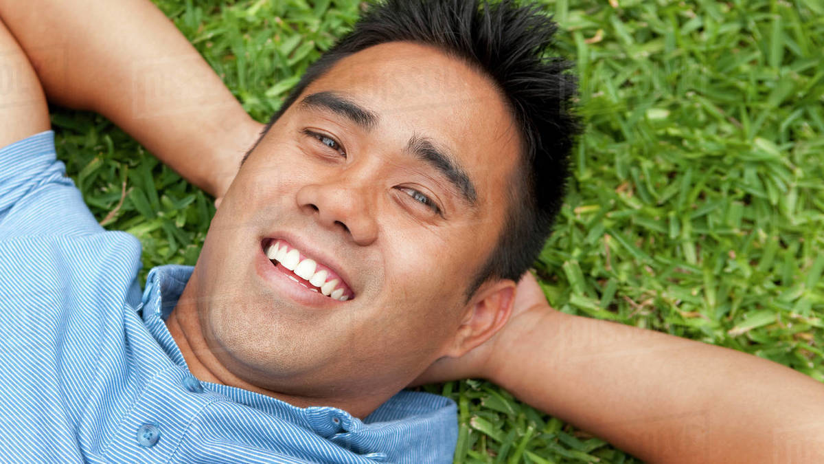 Smiling man laying in grass - Royalty-free Stock Photo | Dissolve