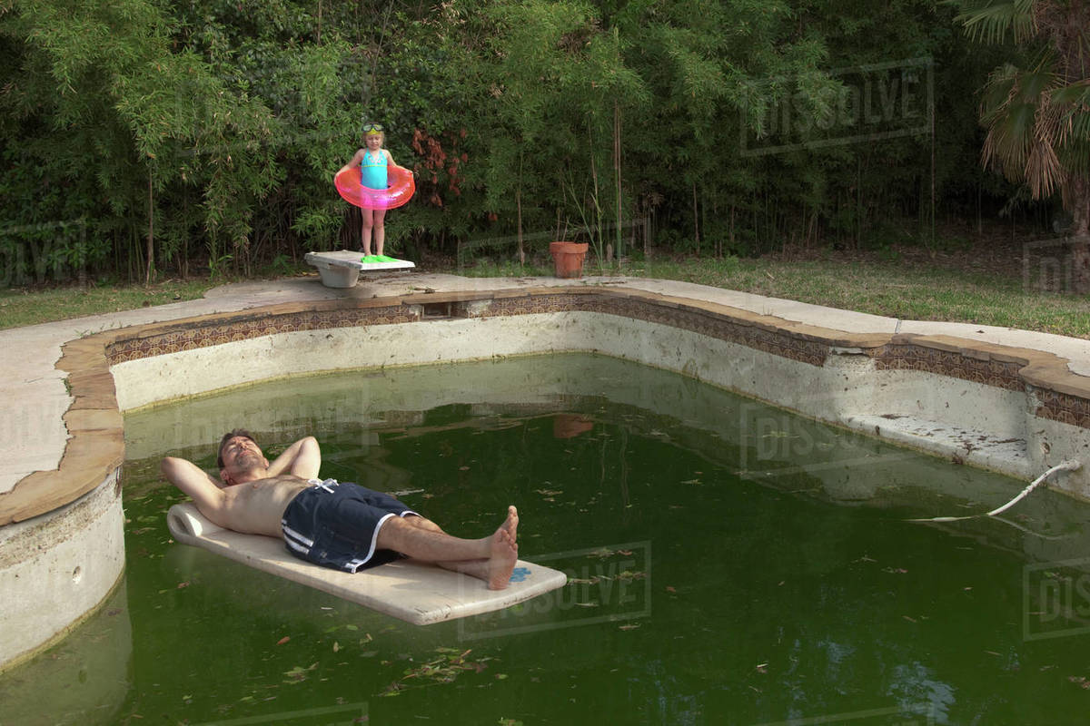 Man floating in dirty swimming pool - Stock Photo - Dissolve