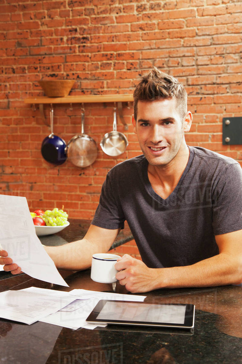 Caucasian man looking at paperwork in kitchen - Royalty-free Stock ...