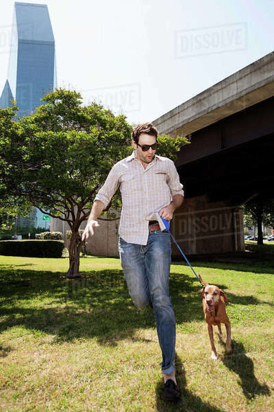 Man walking dog in urban park - Royalty-free Stock Photo | Dissolve